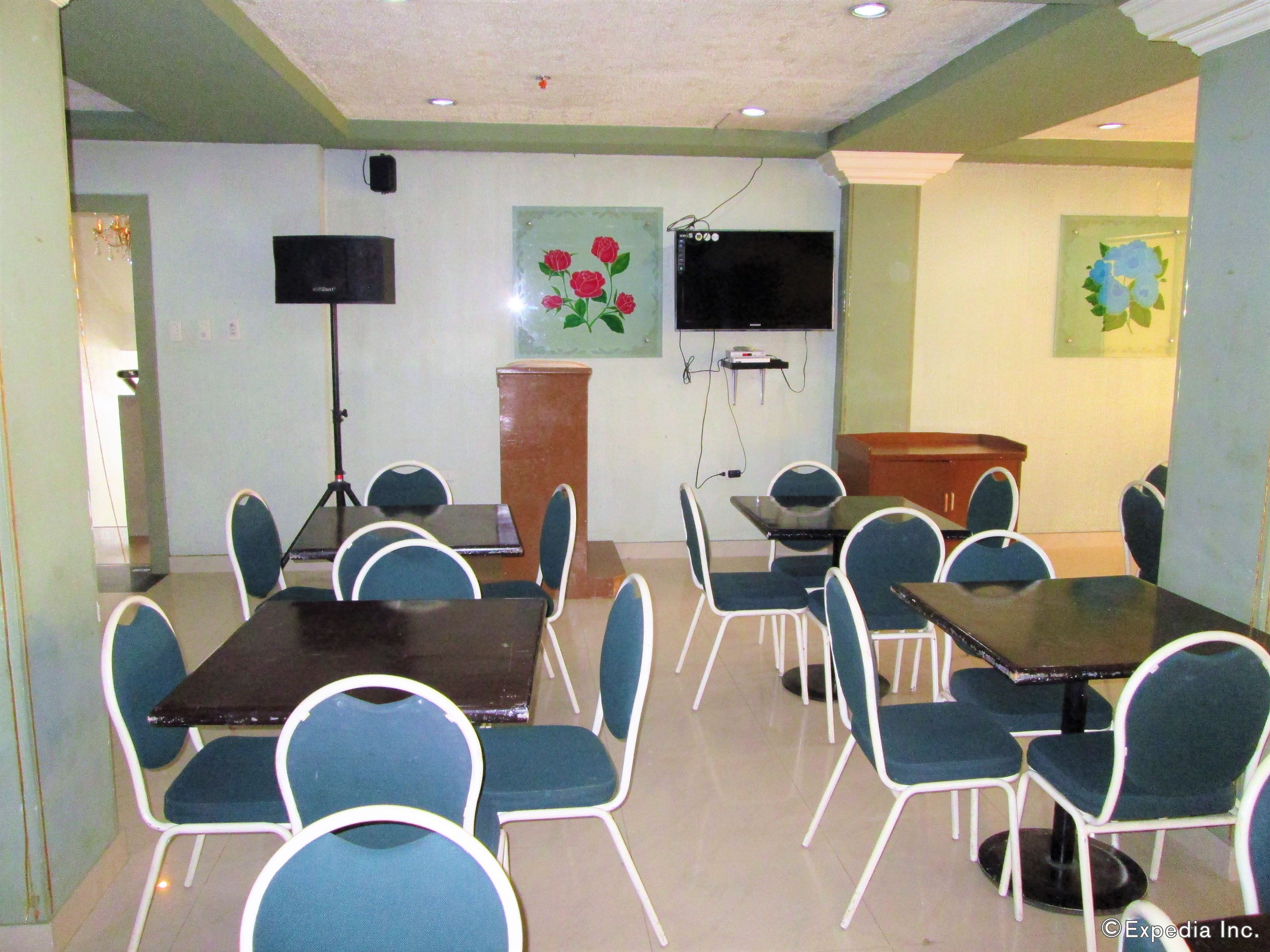 Uma sala de conferências com mesas, cadeiras, um projetor, uma tela e um orador.