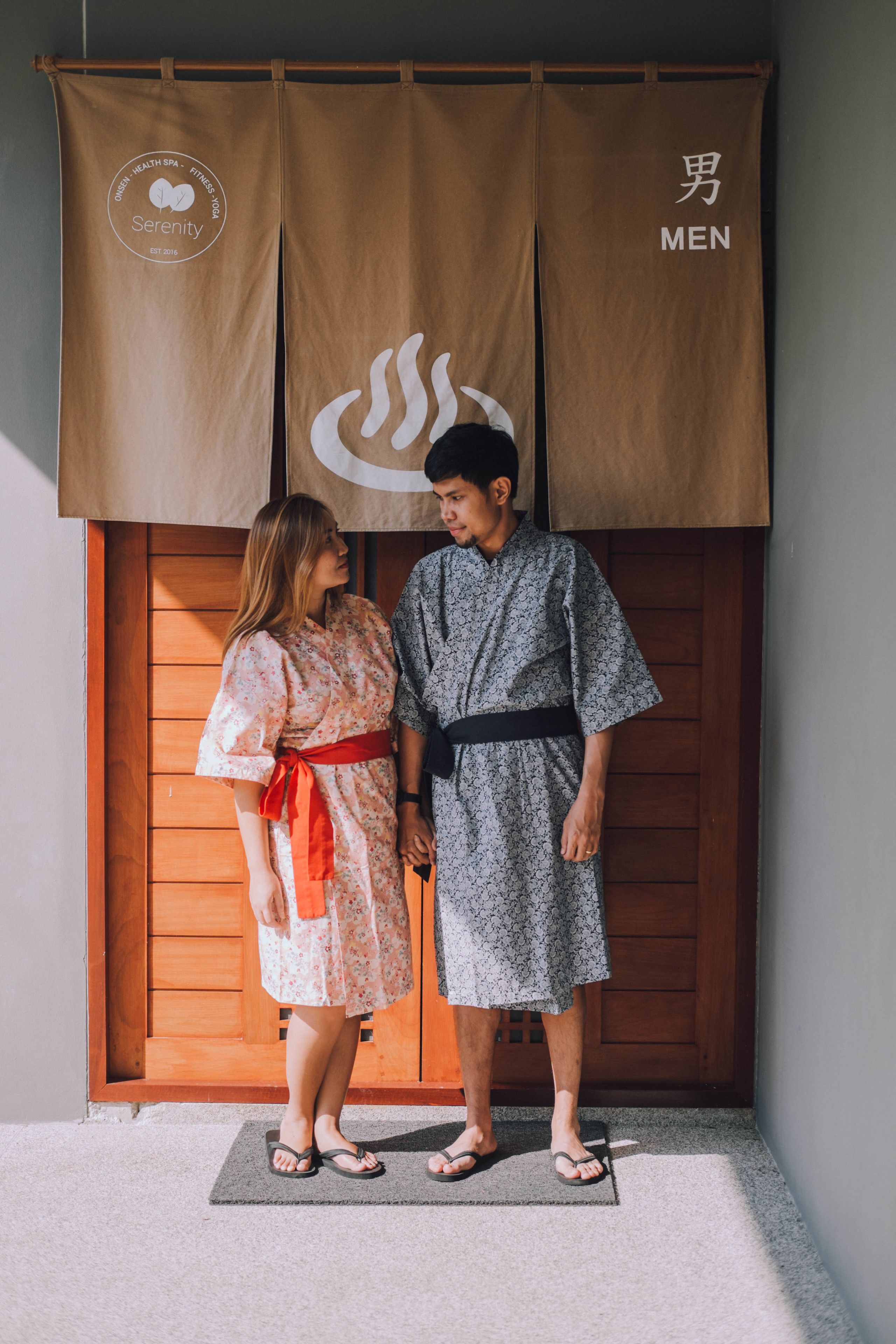 Duas pessoas em frente a uma porta de madeira com uma faixa em cima.