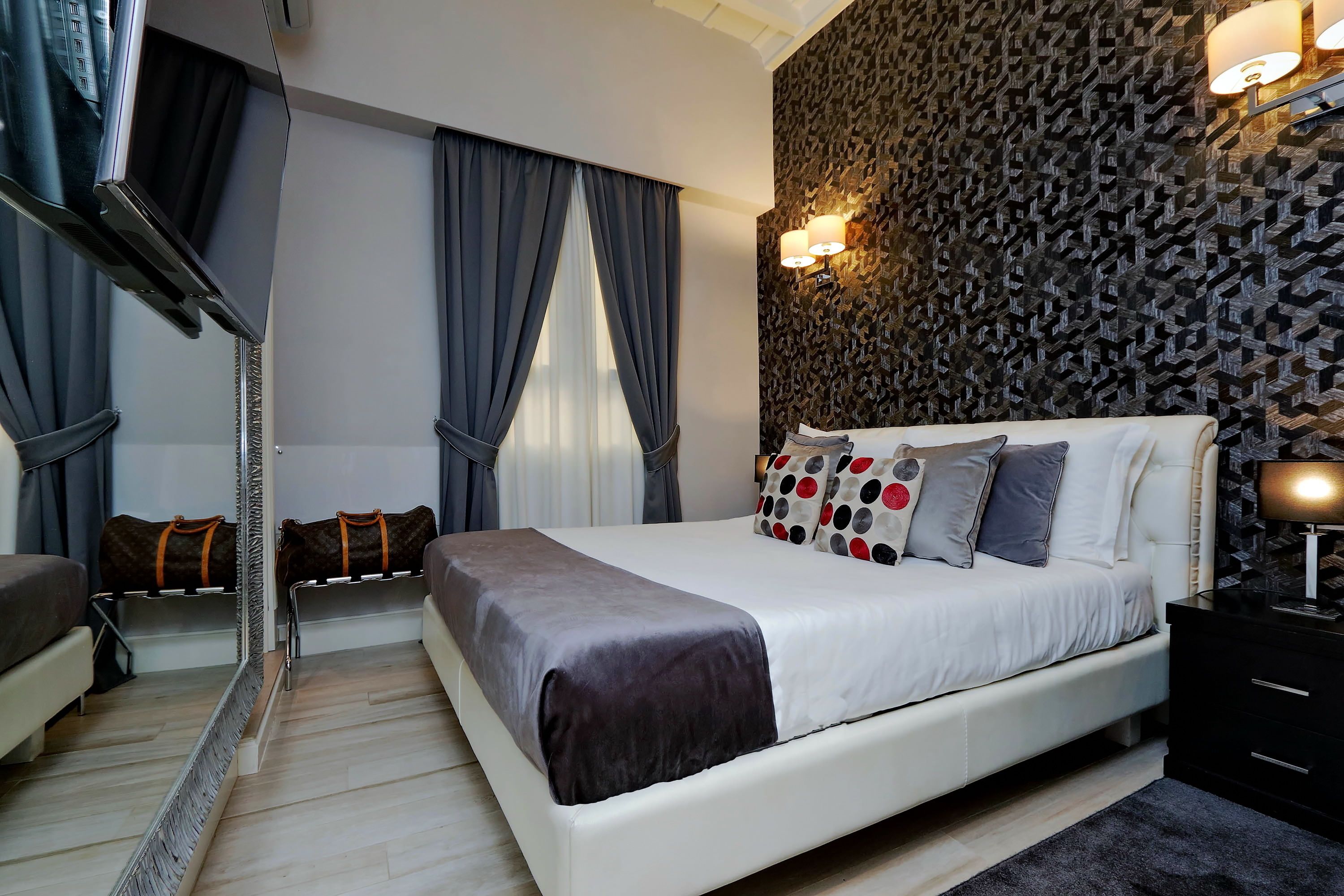 Quarto moderno com uma cama grande, um espelho, um guarda-roupa e uma parede estampada.
