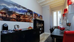 Uma cozinha moderna com uma ilha preta, um espaço de refeições com uma cadeira vermelha e um grande quadro com vista para a cidade.