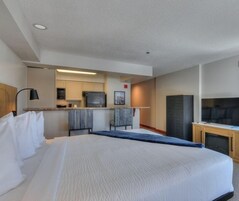 Quarto de hotel com uma cama grande, cozinha compacta, televisão e área de trabalho.