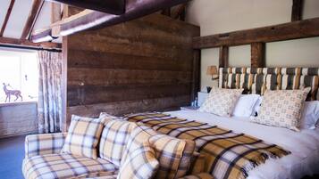 Quarto aconchegante com cama, sofá e teto de madeira.
