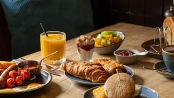 Uma mesa de café da manhã com croissants, muffins e uma saladeira de frutas.