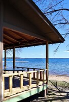 Um deck de madeira com mesa e cadeiras, com vista para um lago calmo.