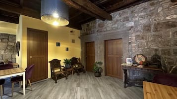 Um interior rústico com parede de pedra, móveis de madeira e luminária pendente.