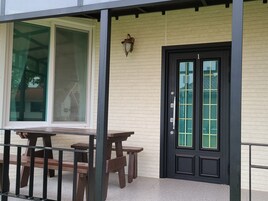 Fachada de um edifício com porta preta, uma janela e uma pequena mesa com bancos.