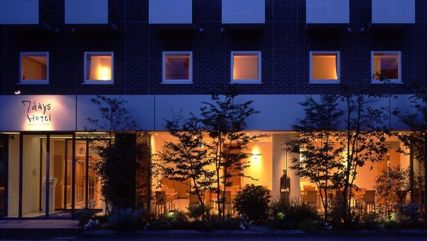 Um hotel com fachada moderna, várias varandas e entrada bem iluminada.