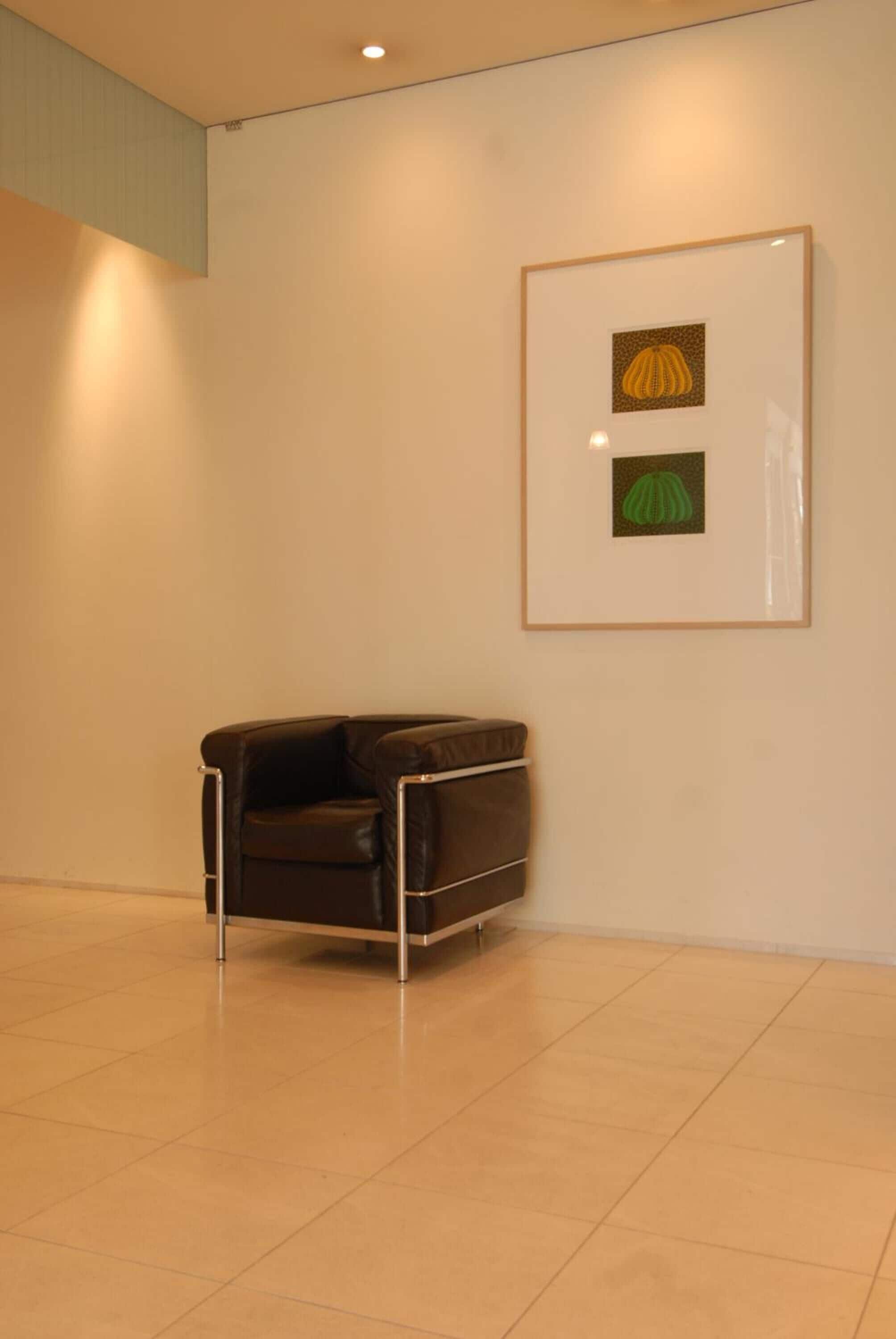 Um quarto com uma poltrona de couro, uma obra de arte emoldurada na parede e piso ladrilhado.