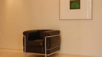 Um quarto com uma poltrona de couro, uma obra de arte emoldurada na parede e piso ladrilhado.