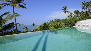 Céu azul claro, piscina e palmeiras.
