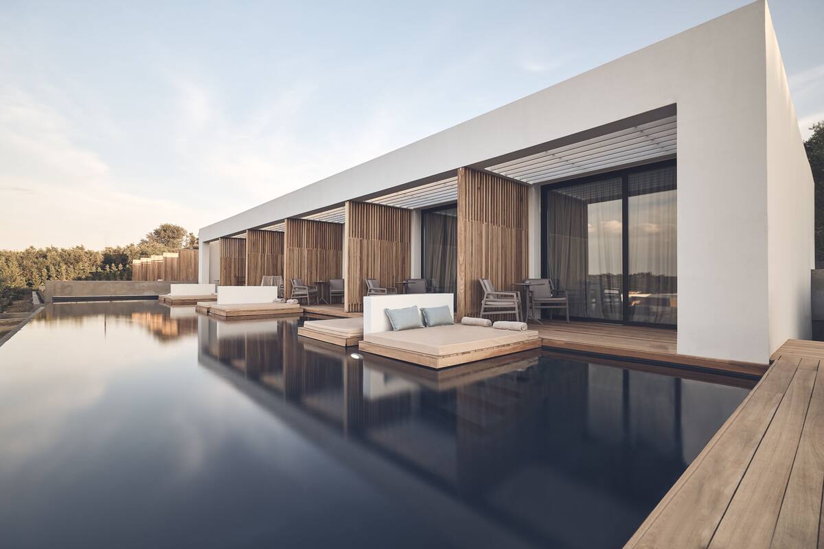 Uma área de piscina moderna ao ar livre, com design minimalista, apresentando um longo banco e opções de assento.