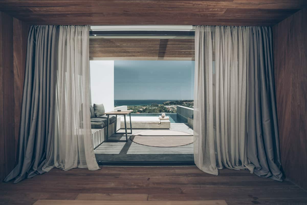 Quarto com vista para o mar, um sofá, uma mesa e cortinas.