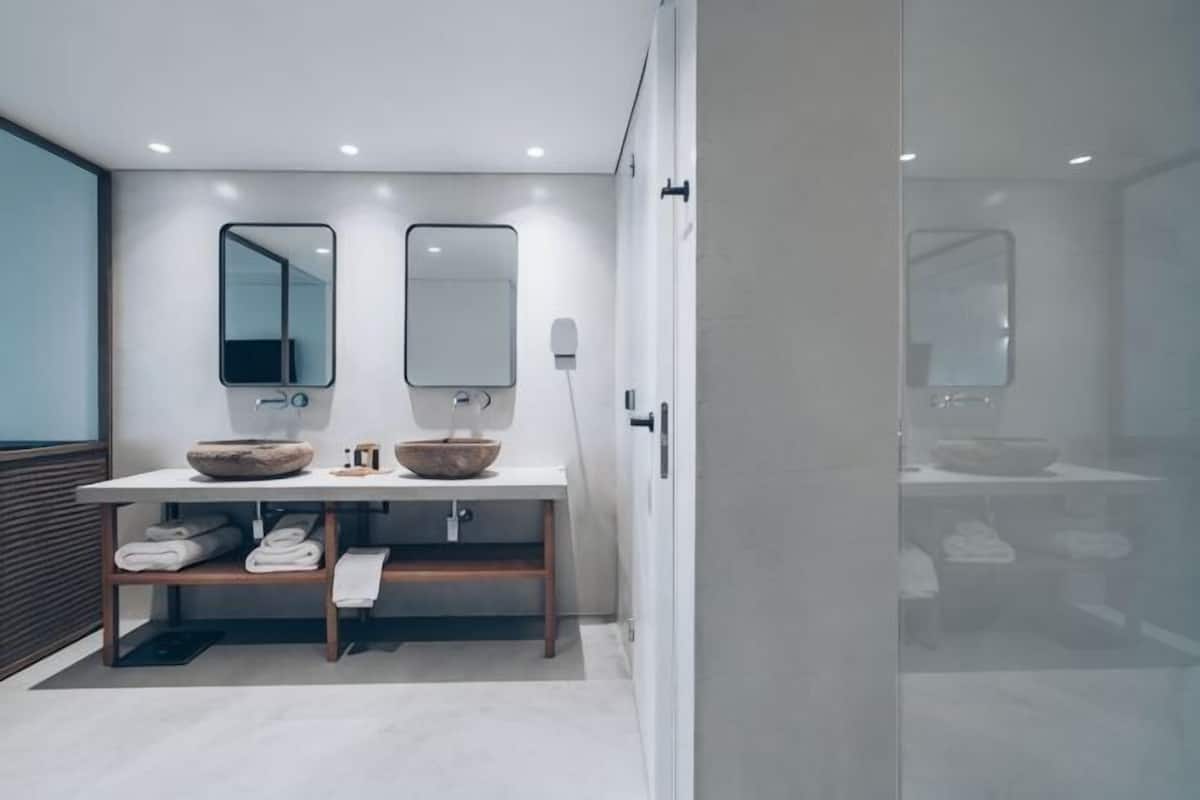 Casa de banho moderna com duas lavatórios, espelhos e zona de duche.