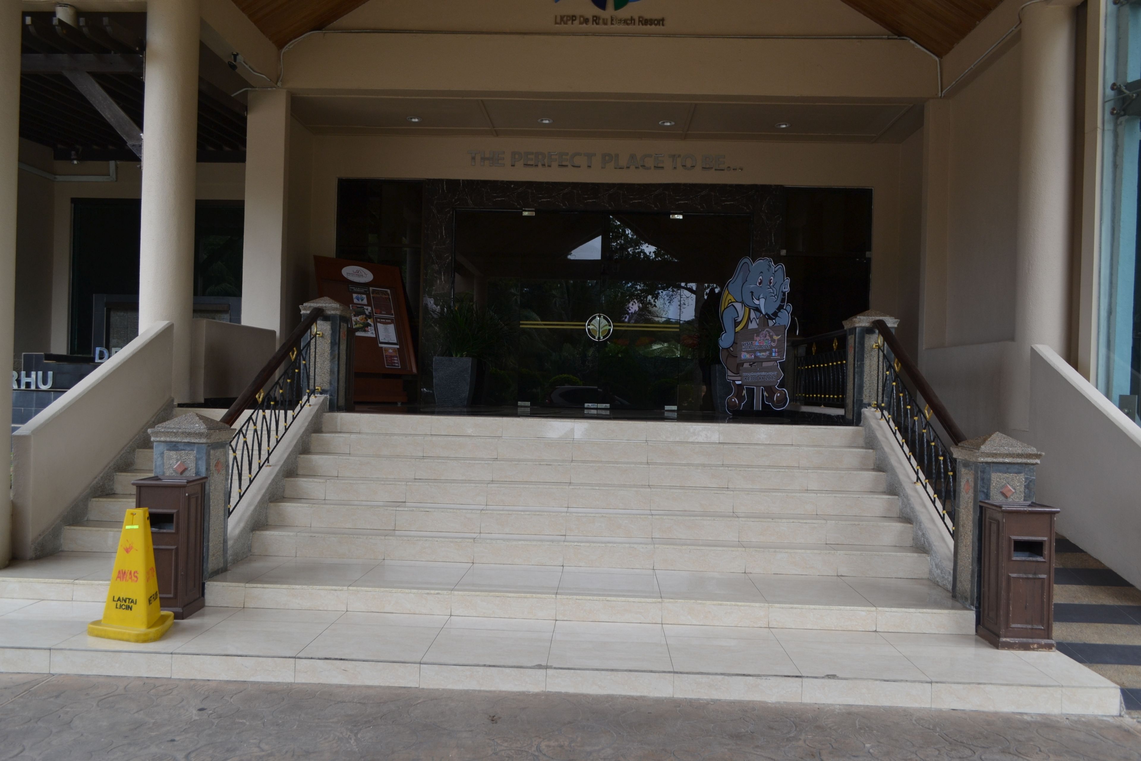 Entrada de hotel com uma escadaria que leva a uma área de recepção.