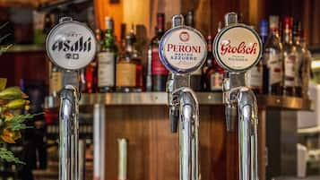 Três torneiras de cerveja com rótulos de marcas como Asahi, Peroni e Grolsch.