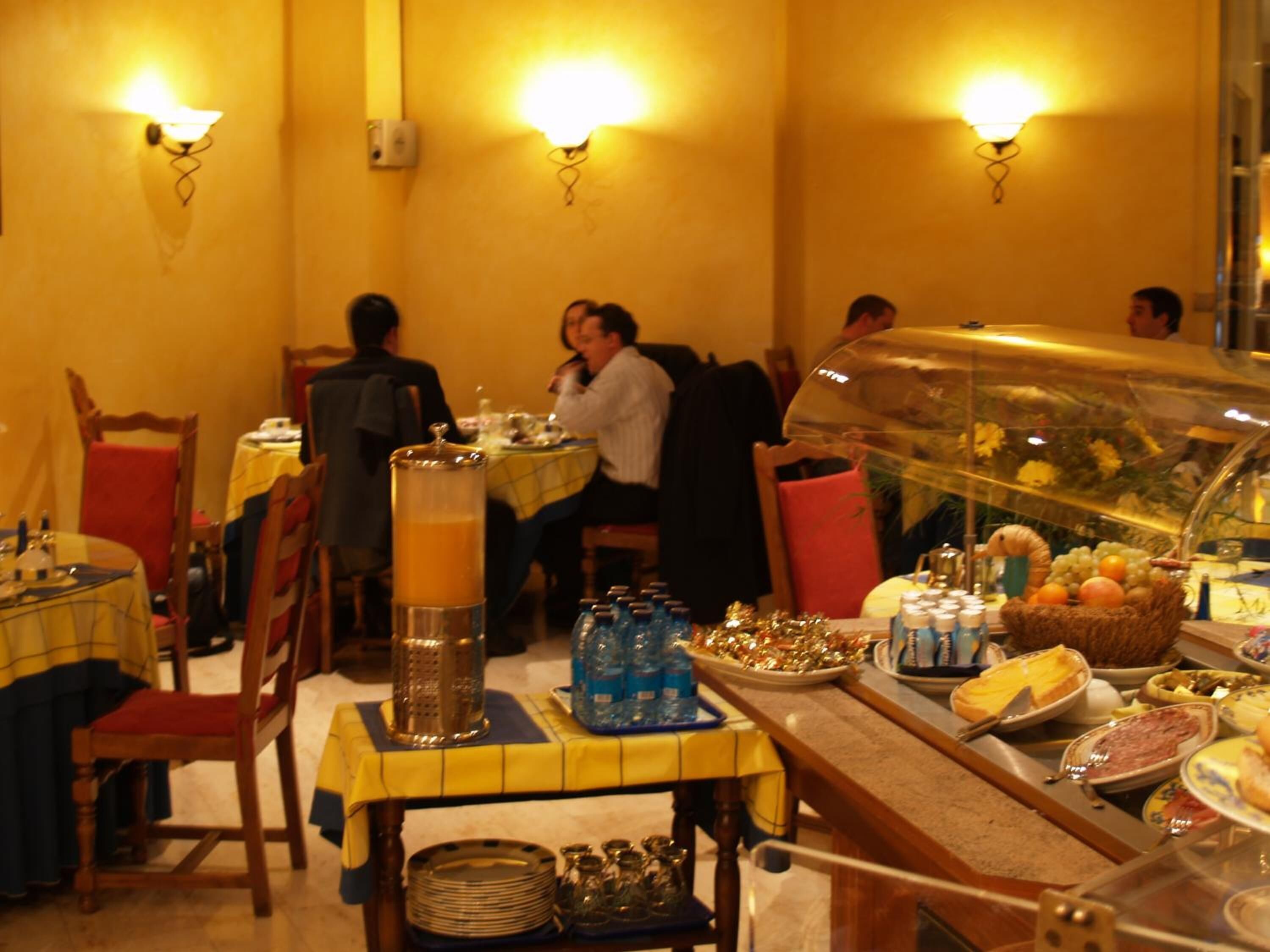 Uma área de buffet com diversos alimentos e um dispensador de suco.