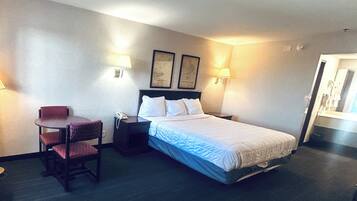 Quarto de hotel com cama, escrivaninha, cadeira e duas luminárias fixadas na parede.