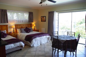 Quarto com duas camas, uma mesa de jantar com cadeiras e uma varanda com guarda-corpo.
