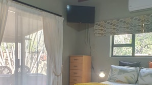 Quarto com cama, televisão, guarda-roupa e janela.