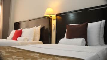 Quarto de hotel com duas camas, cabeceira de madeira, abajur e painel de controle na parede.