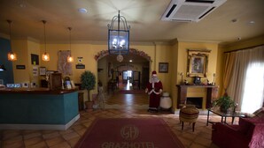 Um hall de hotel com balcão de recepção, uma estátua do Papai Noel, lareira e tapete vermelho com o nome do hotel.