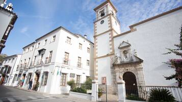 Um edifício histórico com uma torre do relógio, fachada branca e uma placa com a inscrição "Hotel Plerta Villa".