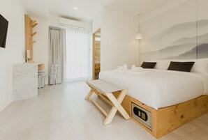 Quarto moderno com cama grande, cabeceira de madeira e um banco.