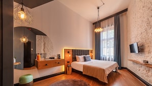 Um quarto moderno com cabeceira de madeira, uma cama grande, mesa de cabeceira, espelho e televisão na parede.