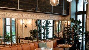 Decoração moderna com assentos em couro, mesas redondas e luminárias esféricas pendentes.