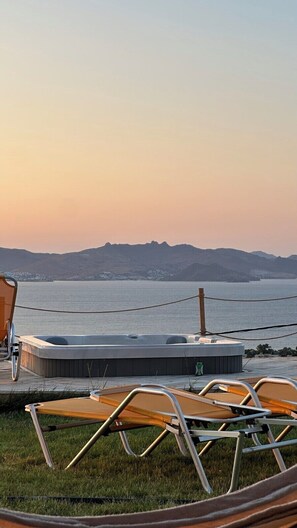 Uma banheira de hidromassagem em um deck com vista para o mar e montanhas.