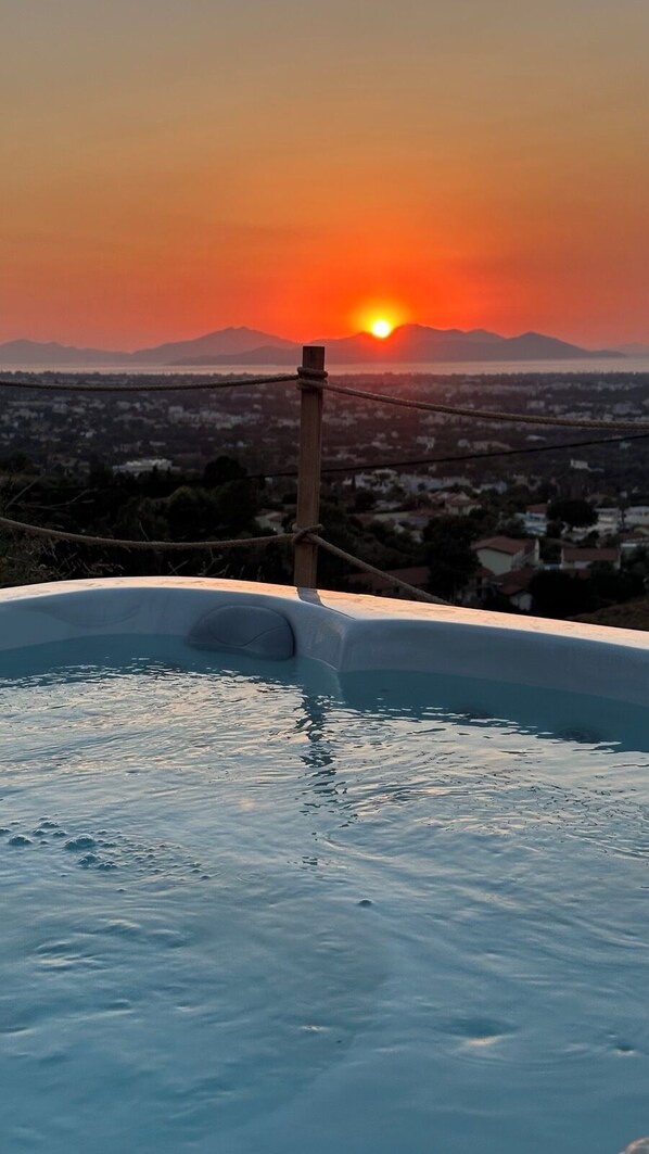 Uma banheira de hidromassagem com vista para um pôr do sol sobre a paisagem urbana.