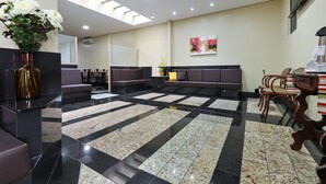 Um hall moderno com piso xadrez, áreas de estar e um balcão de recepção.