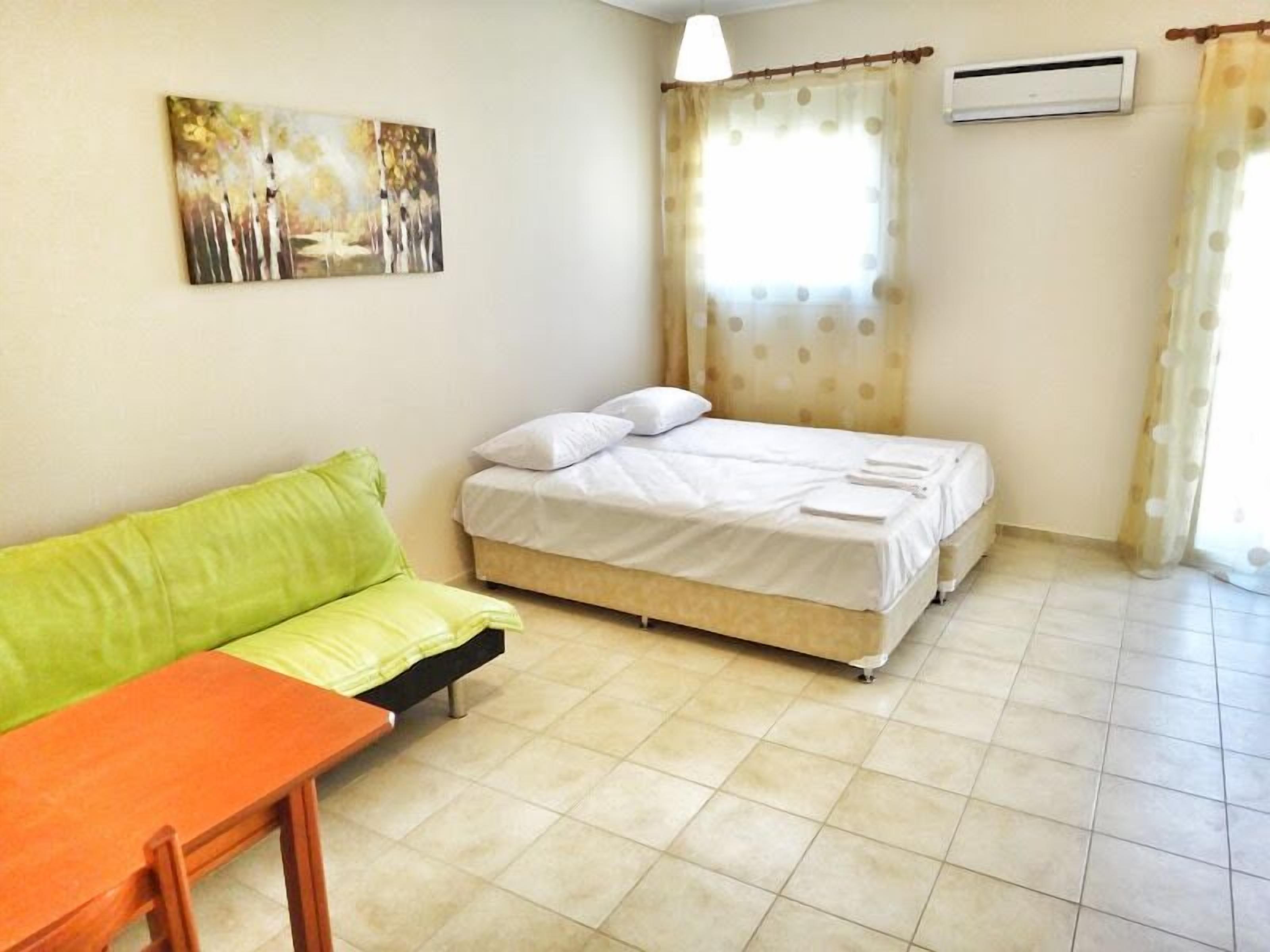 Um quarto com uma cama, um sofá verde, uma mesinha e um quadro na parede.