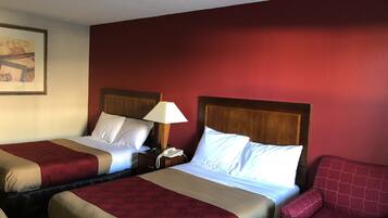 Quarto de hotel com duas camas, parede vermelha e cabeceira de madeira.