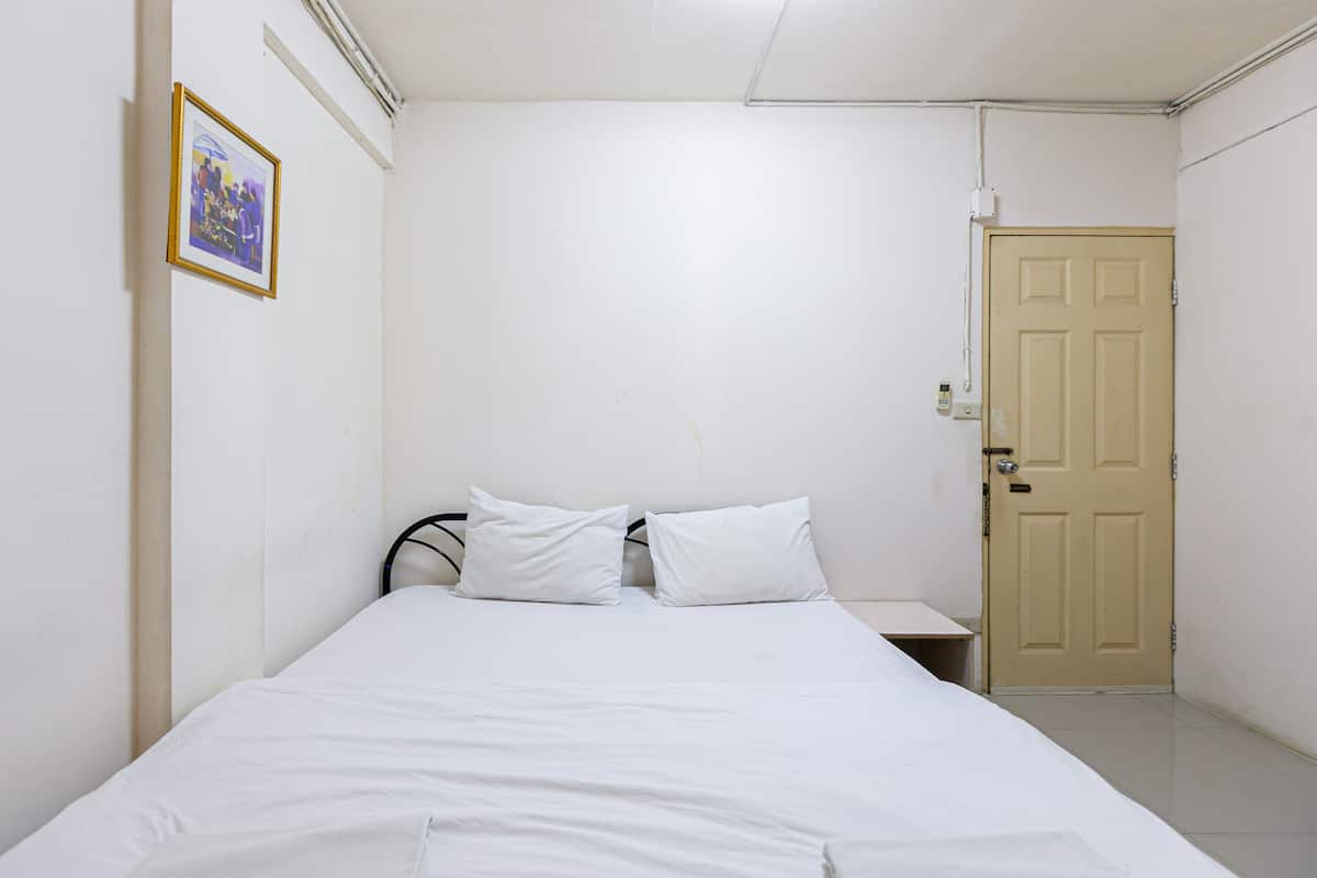 Quarto com cama, porta e quadro fixado na parede.