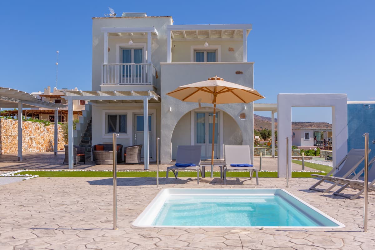 Um edifício moderno com piscina, área de estar externa e céu azul límpido.