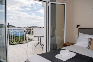Quarto de hotel com cama, uma mesa pequena, uma cadeira e varanda com vista.