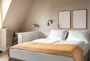 Quarto com uma cama, uma escrivaninha, uma cadeira e duas luminárias fixadas na parede.
