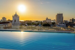 Piscina com paisagem urbana ao fundo durante o pôr do sol.