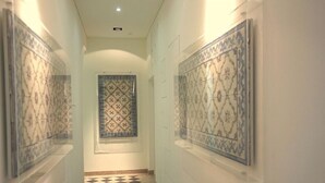 Um corredor com azulejos estampados nas paredes e chão xadrez.
