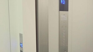 Painel de comando de elevador com visor digital e vários botões.