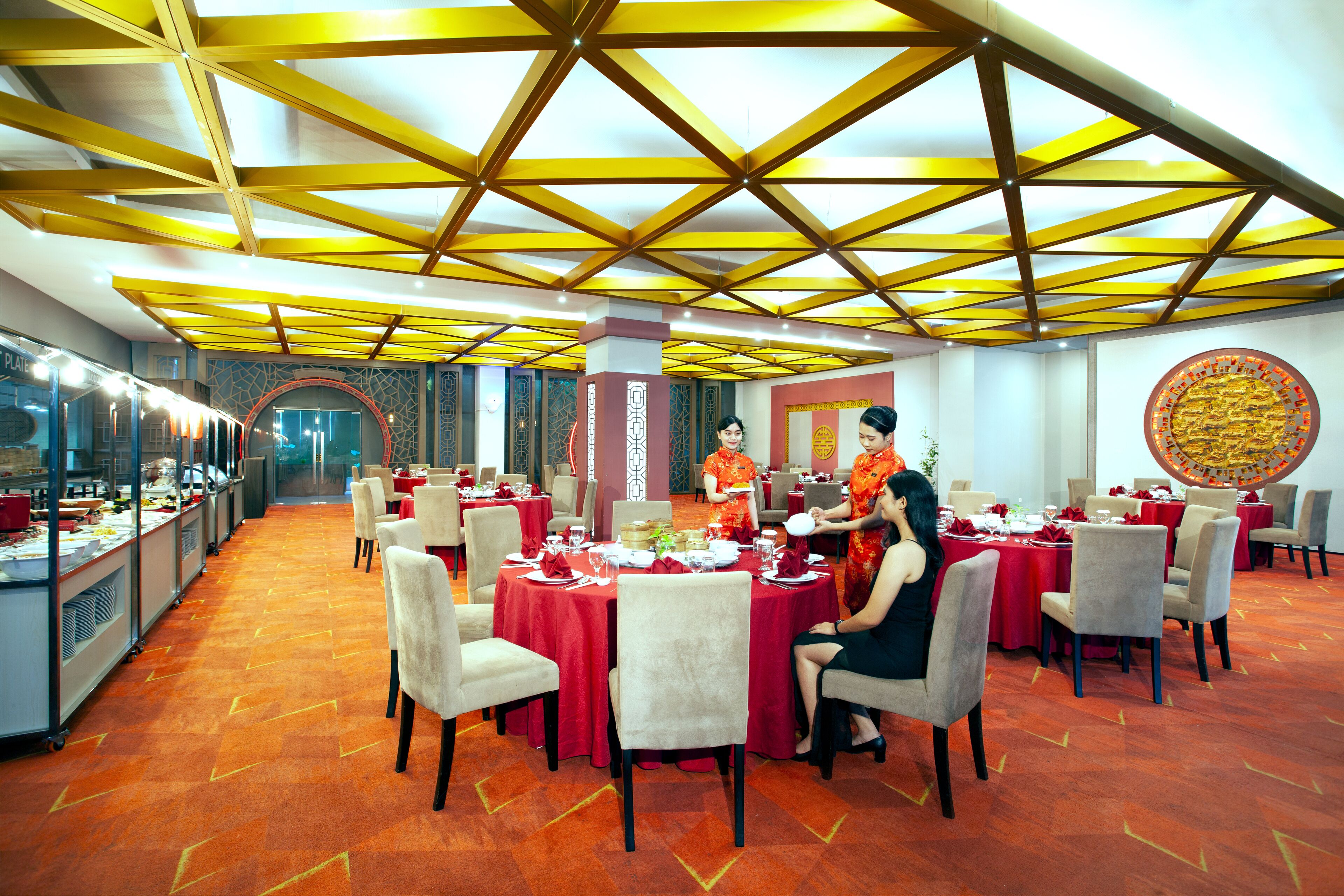 Restaurante com mesas postas para refeições, área de buffet e teto decorativo.