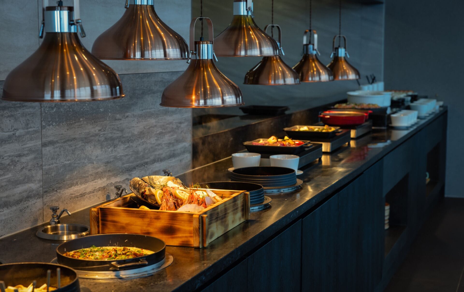 Uma mesa de buffet com diversos pratos e uma caixa de madeira contendo um frango assado.
