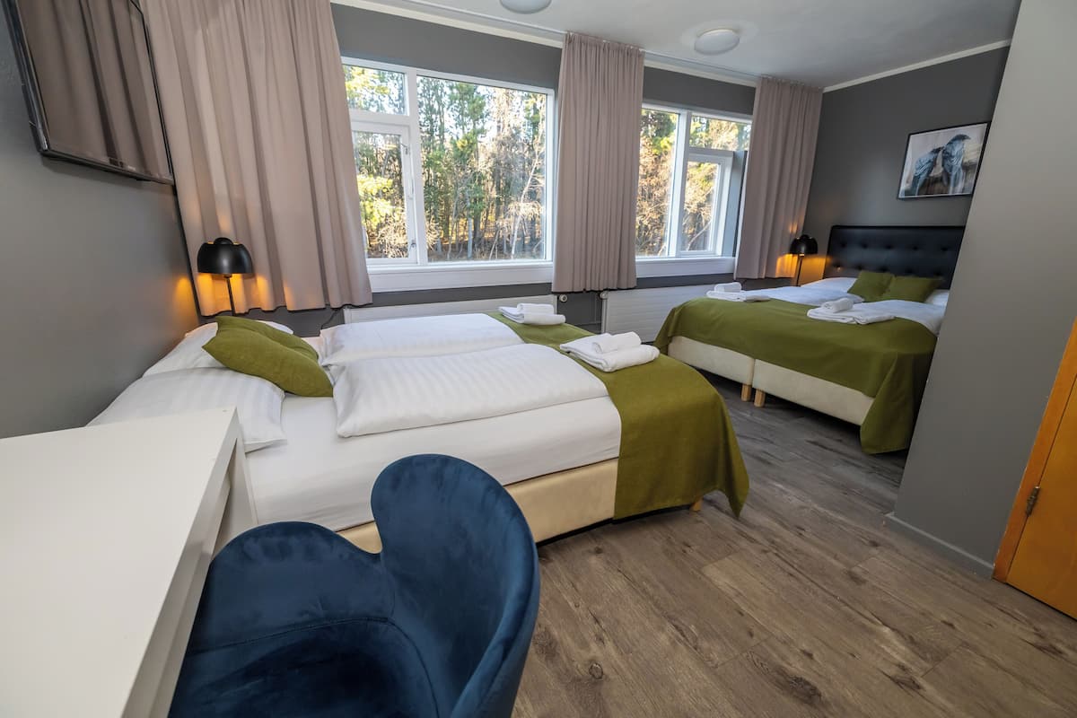 Quarto de hotel com duas camas, uma mesa e uma cadeira.