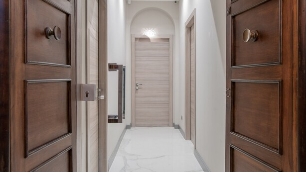 Um corredor com portas de madeira e chão de mármore.