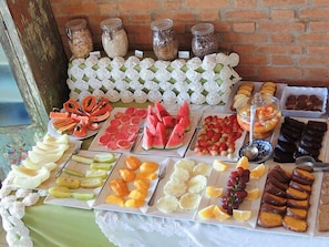 Uma mesa de buffet com diversas frutas e lanches.
