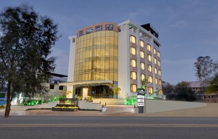 Um hotel moderno com fachada curva, vários andares e entrada bem iluminada.
