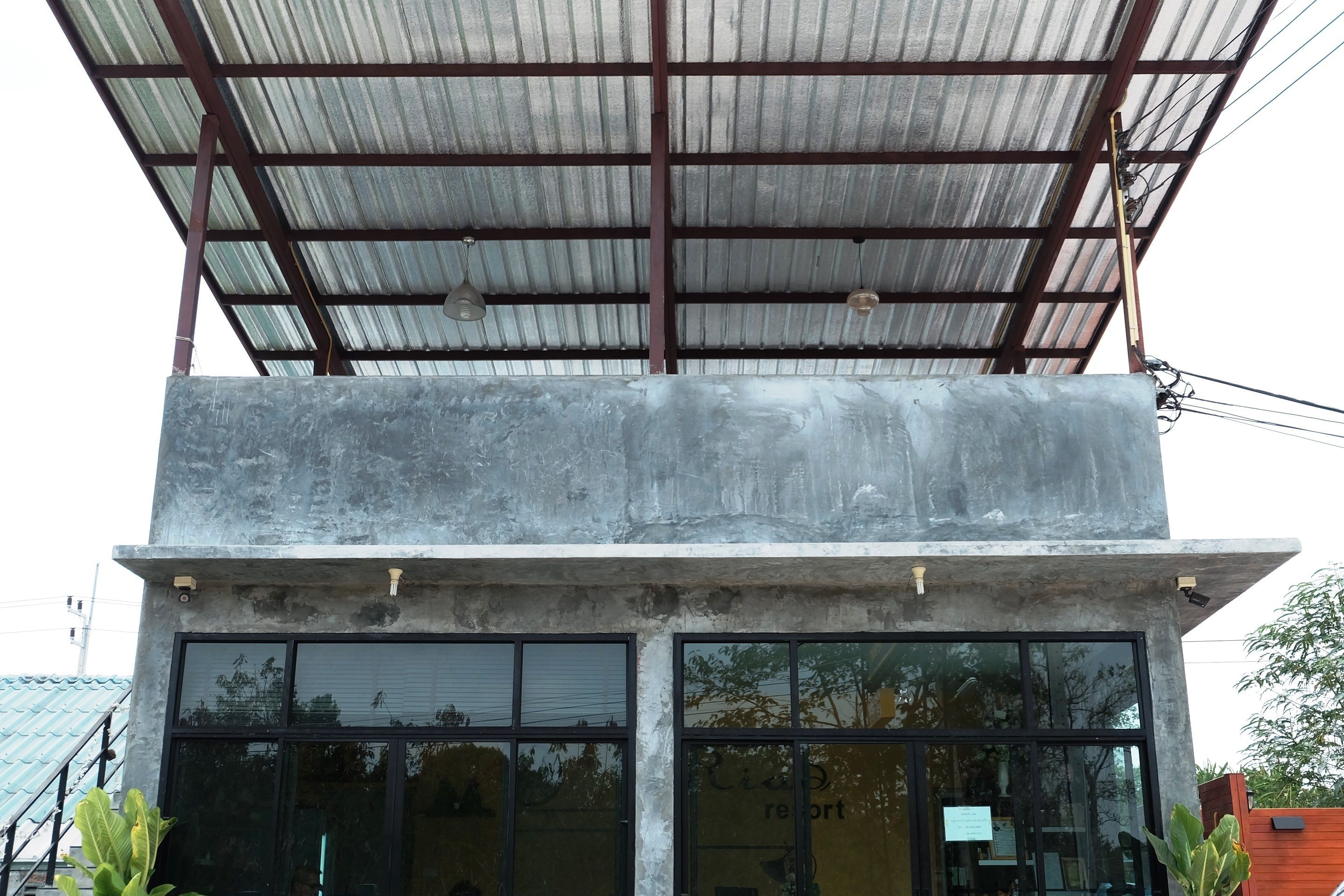 Um edifício com telhado de metal corrugado, janelas amplas e fachada de concreto.
