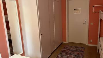 Quarto com cama, mesa de cabeceira, espelho e porta com um cartaz.