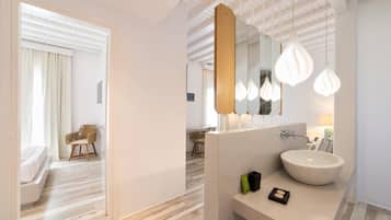 Casa de banho moderna com um espelho grande, uma sanita branca e luzes pendentes.